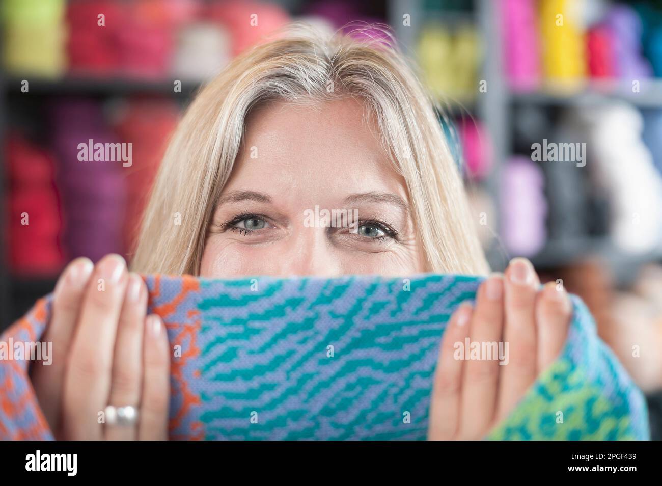 Portrait of a mature woman hiding her face with scarf in coffee shop ...