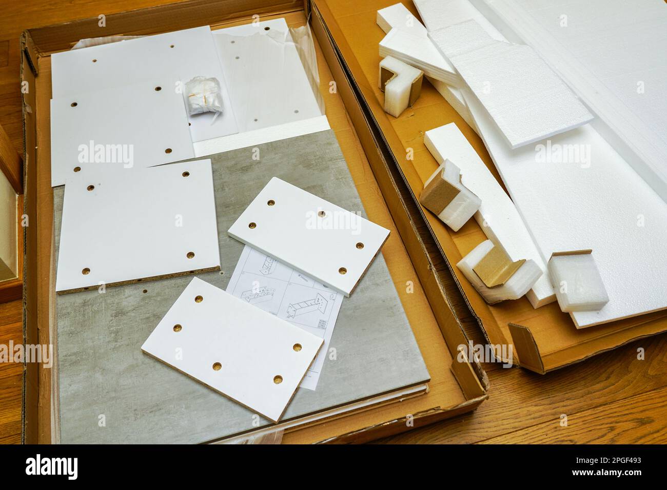 Opened cardboard box with new white and gray laminated chipboard set ...