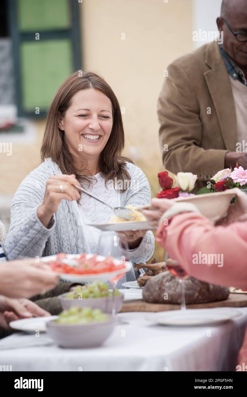 Woman with family sharing food and serving each other Stock Photo - Alamy