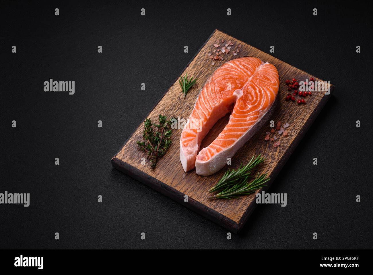 Fresh raw red fish steak with spices and herbs on a dark concrete ...