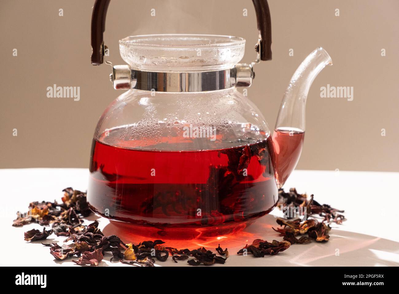 Red hibiscus tea from the petals of a Sudanese rose in a glass teapot ...