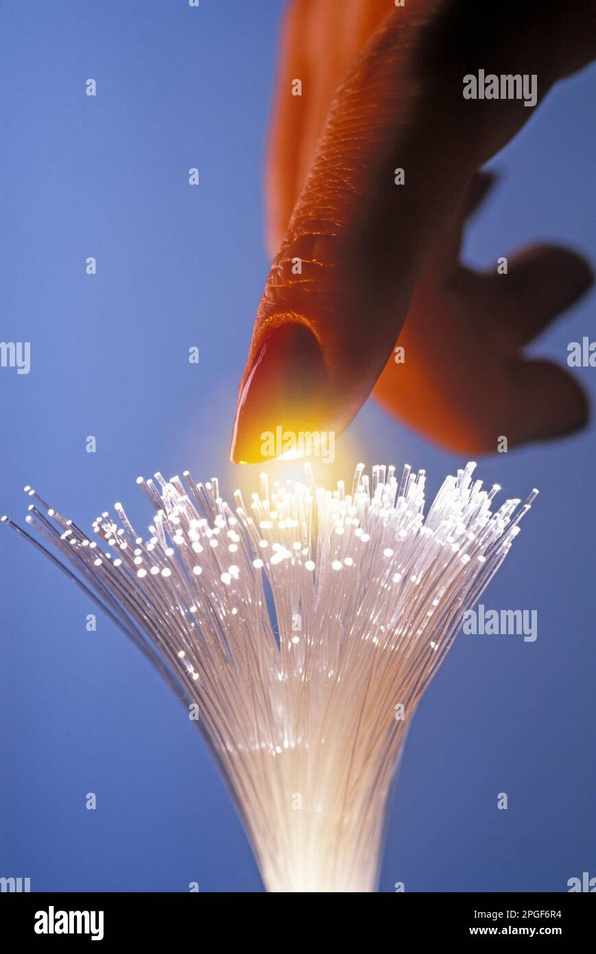 WOMANS INDEX FINGER TIP TOUCHES LIT TIPS OF FIBER OPTIC STRANDS (©KECK ...