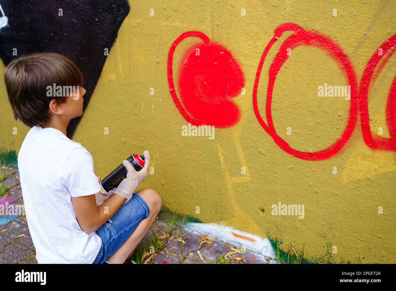 Boy drawing graffiti on the city wall Stock Photo - Alamy