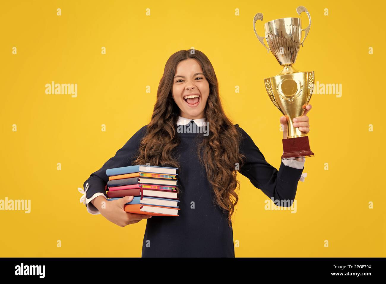 Excited schoolgirl in school uniform celebrating victory with trophy ...