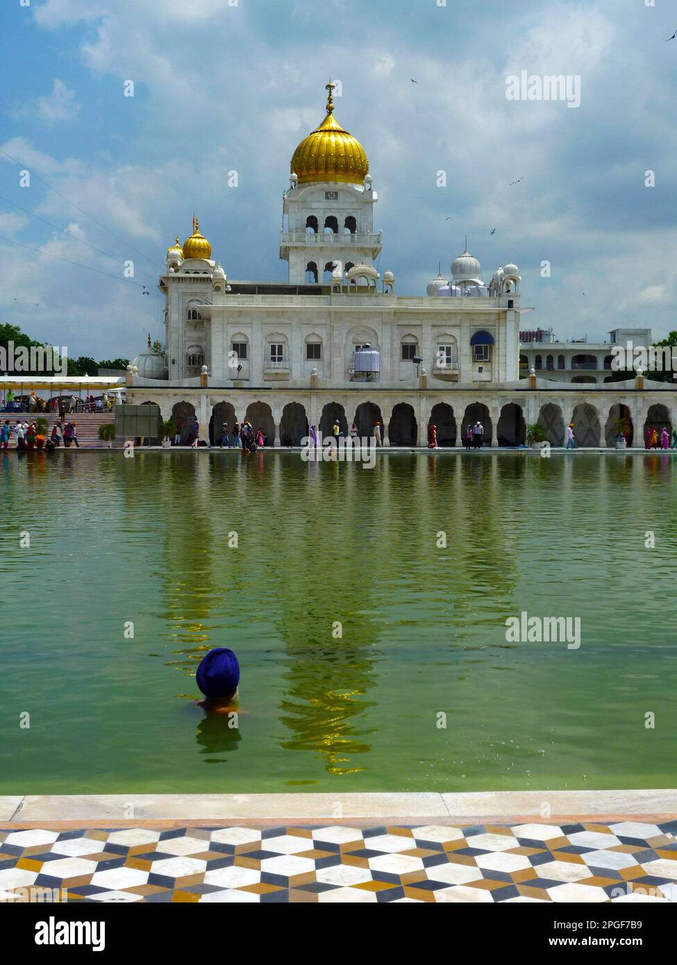 The Golden Temple and back view of a man with a turban in the water ...