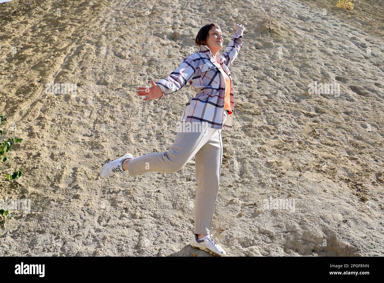 A woman stands on one leg against the background of an embankment Stock ...