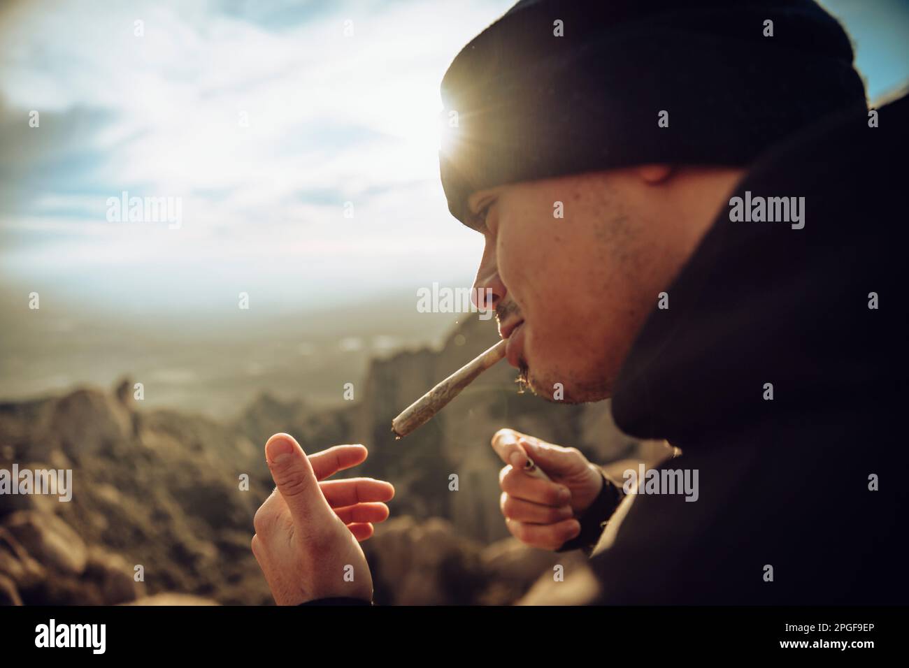 Boy smoking a marijuana joint on top of a mountain during sunset Stock ...