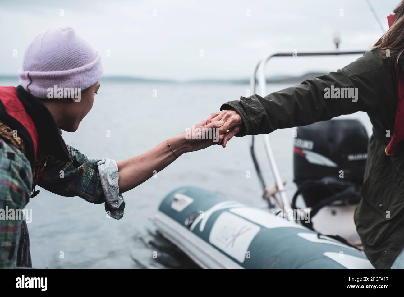 Women helps person onto boat with hands in Scotland Stock Photo - Alamy