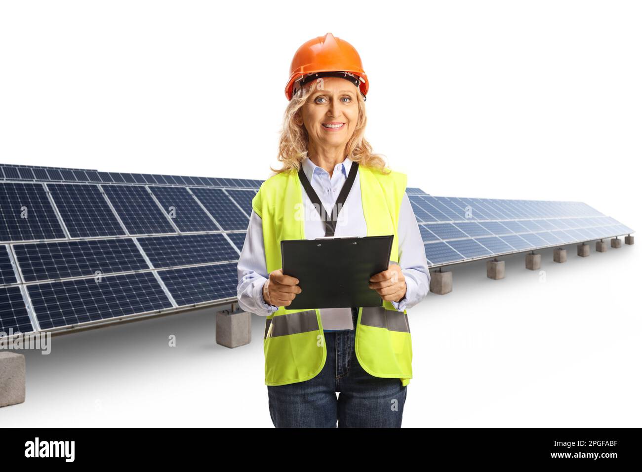 Female engineer with a safety vest and hardhat smiling and standing in front of a solar panel ...