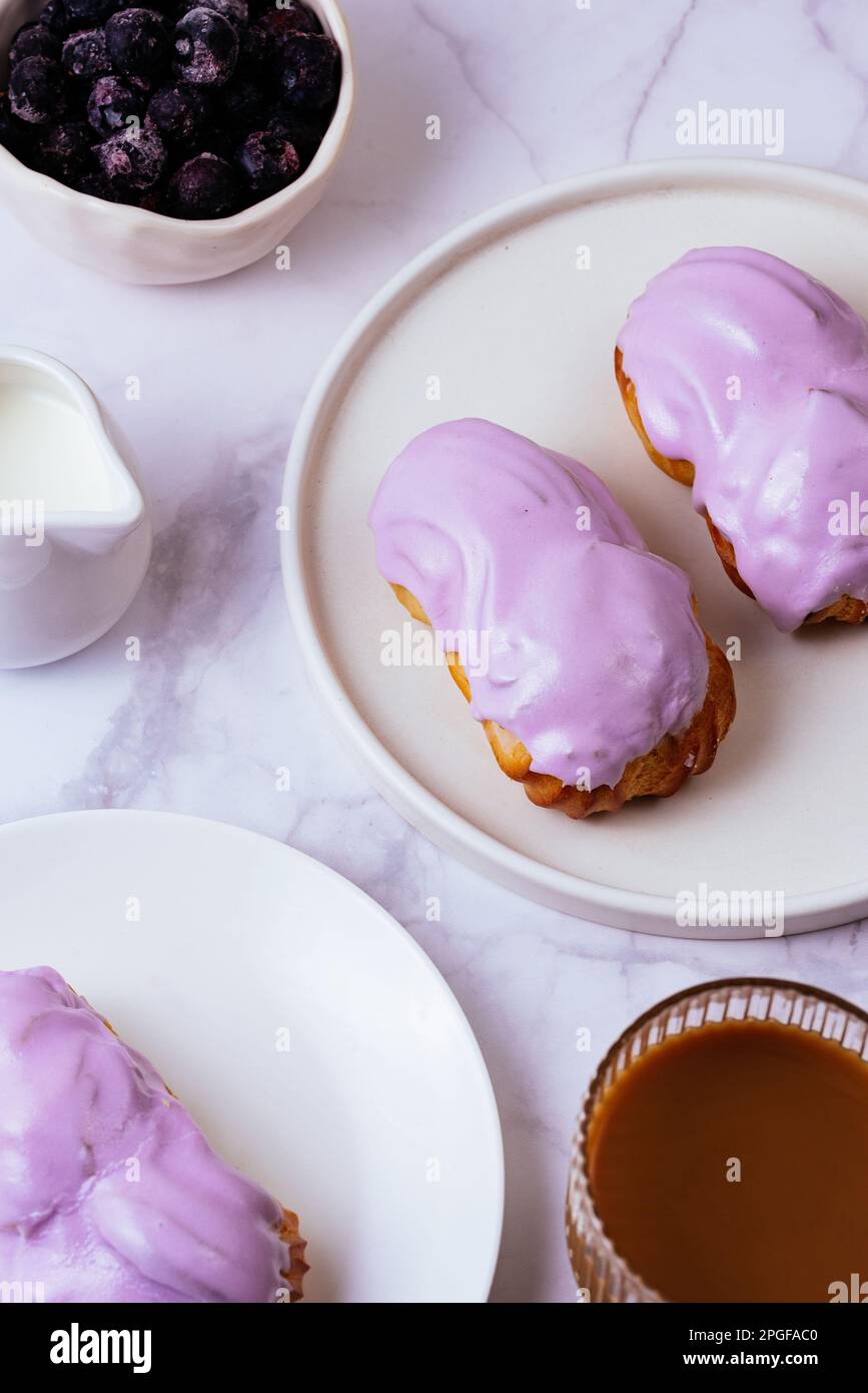 eclair in purple berry glaze and coffee with milk in a glass Stock ...