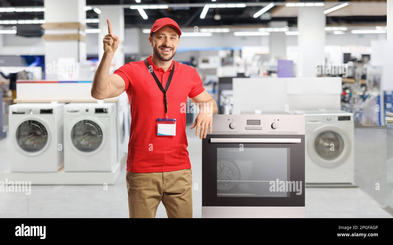 Salesman with electrical appliances smiling and pointing up inside a ...