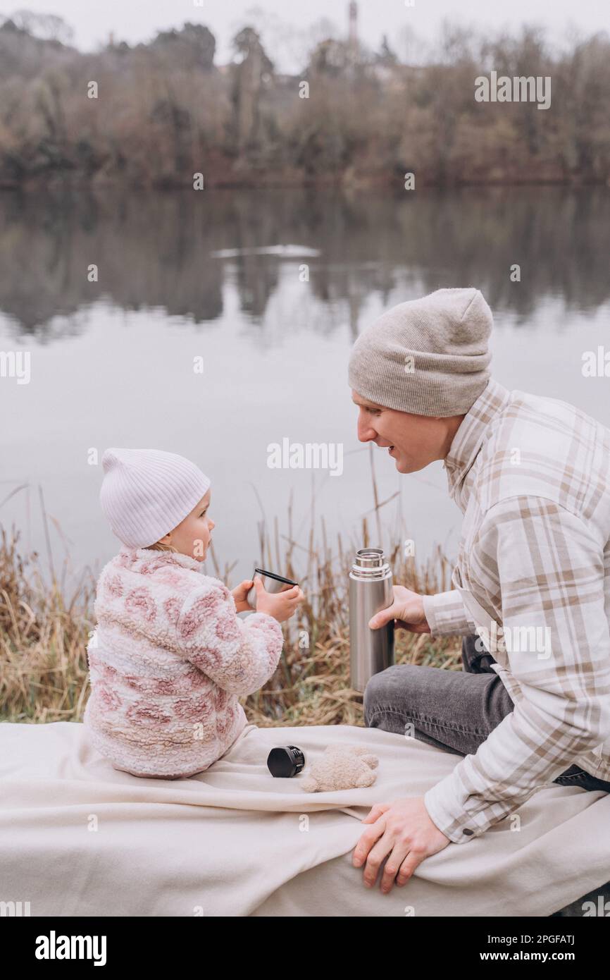 Dad and baby daughter are sitting by the river and drinking tea Stock ...