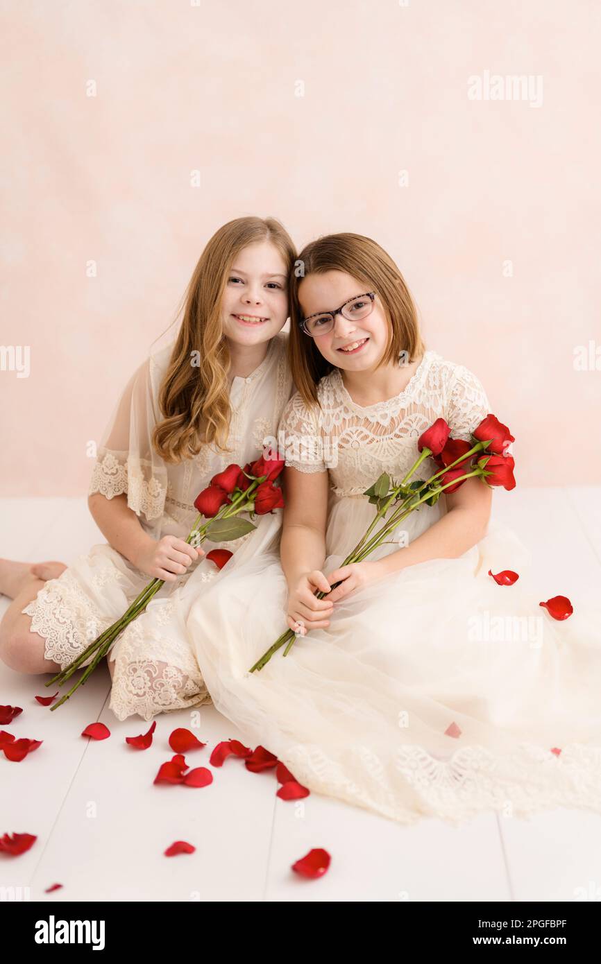 Two sisters sitting holding roses for Valentine's Day Stock Photo - Alamy