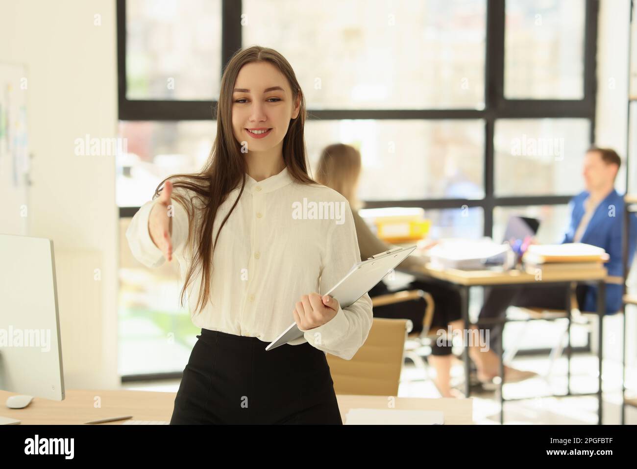 Positive manager holds clipboard stretching hand to greet Stock Photo ...