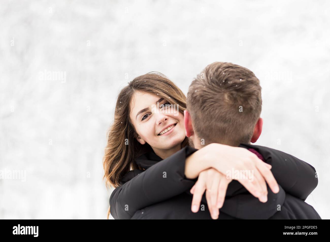 woman hugs her husband's neck in a winter park Stock Photo - Alamy