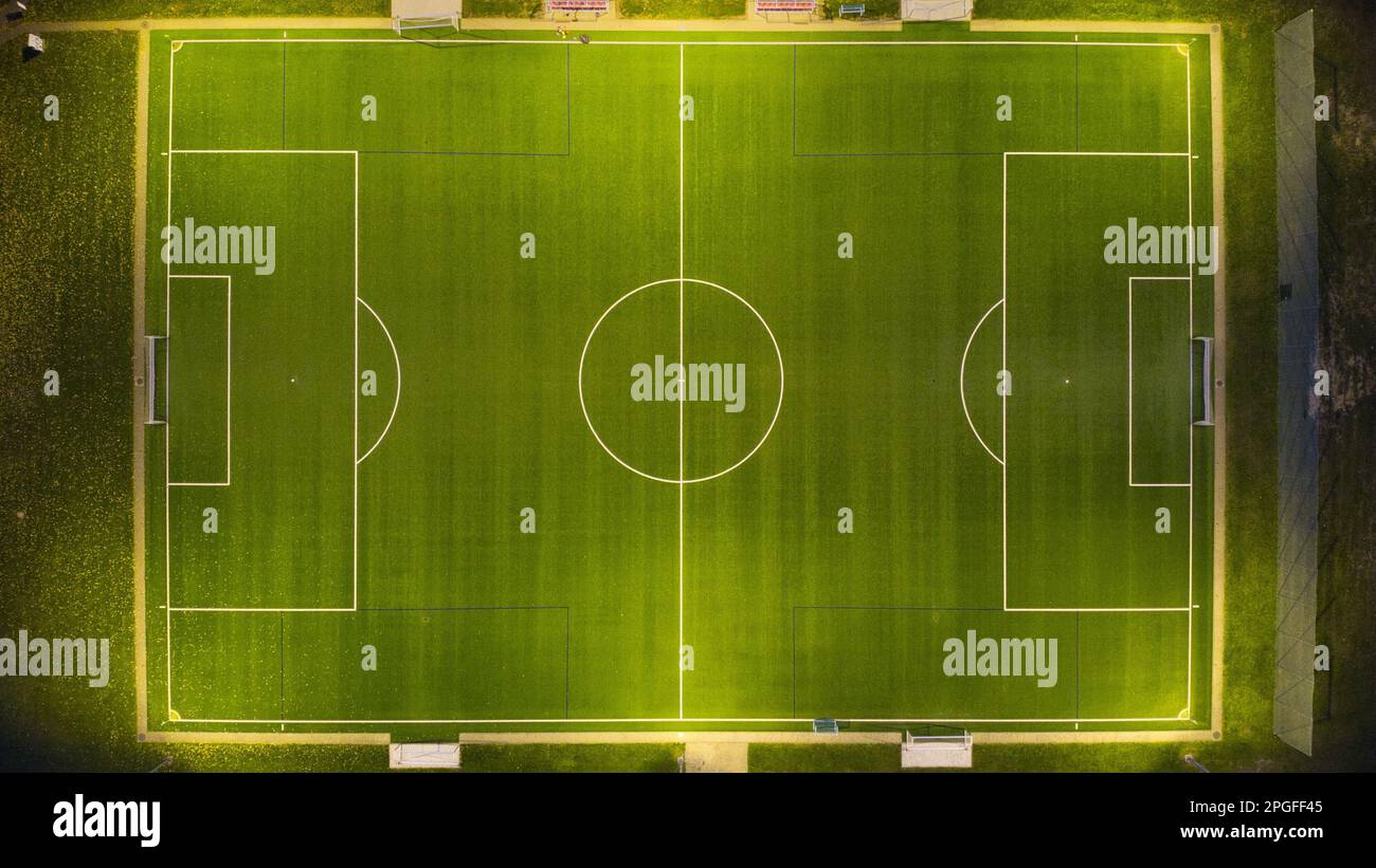 Aerial view of a lush green football sports field in an empty stadium ...
