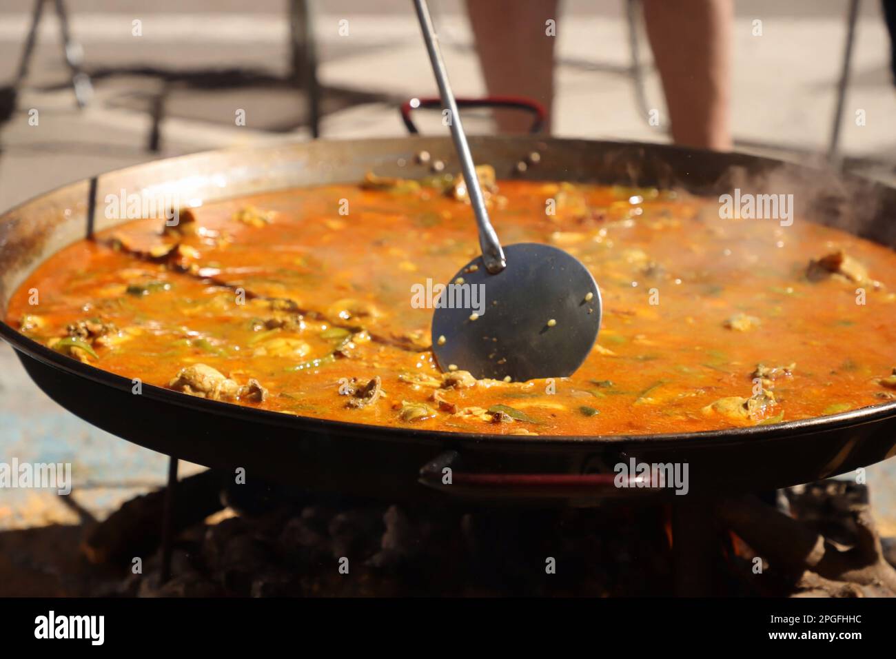 A street traditional cooking with a large stainless steel frying pan in ...