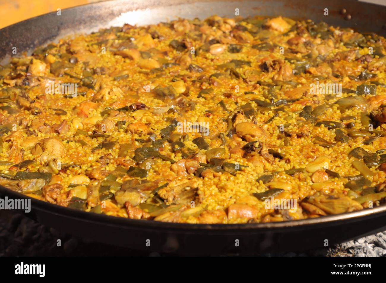 A street traditional cooking with a large stainless steel frying pan in ...