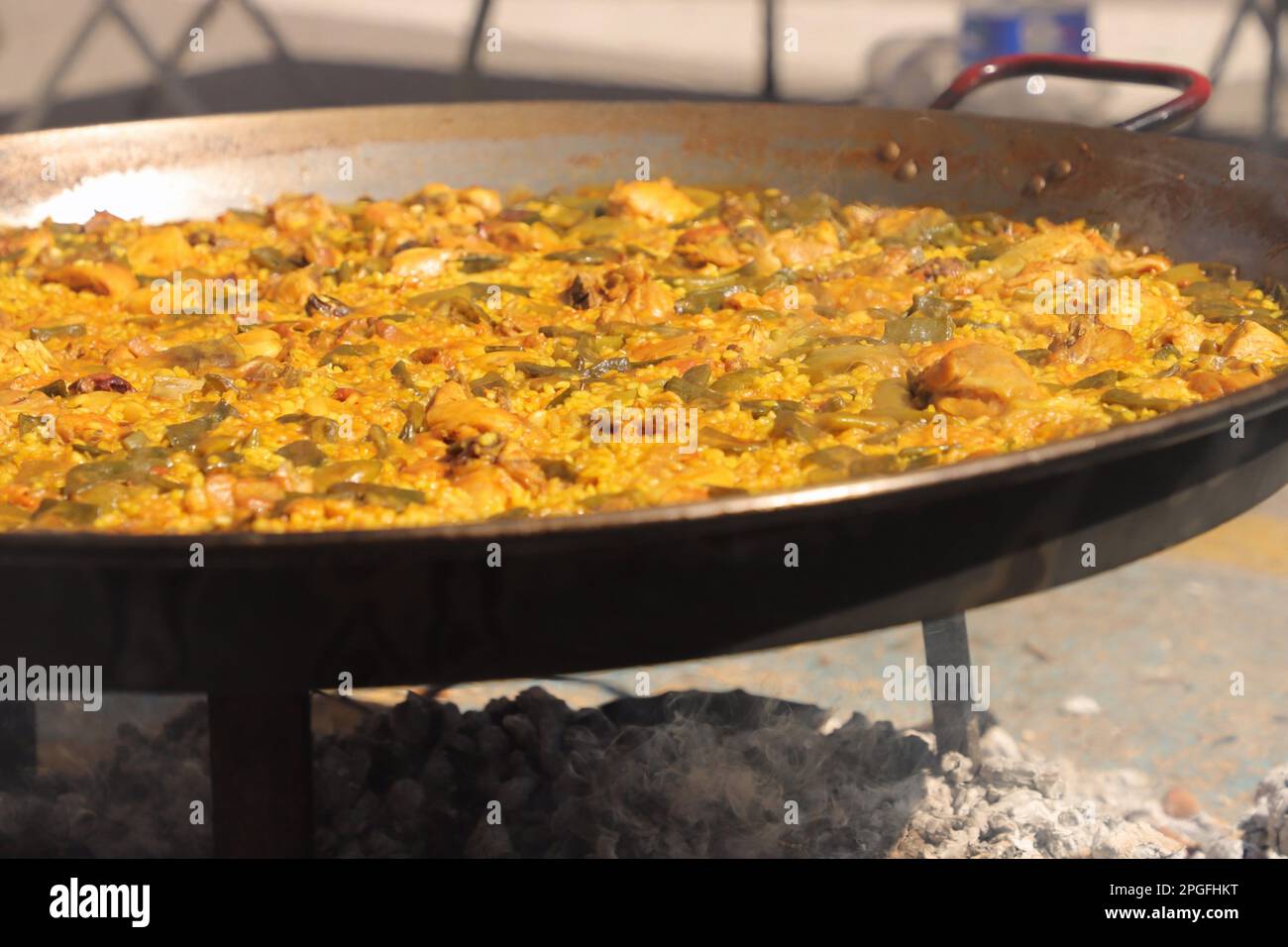 A street traditional cooking with a large stainless steel frying pan in ...