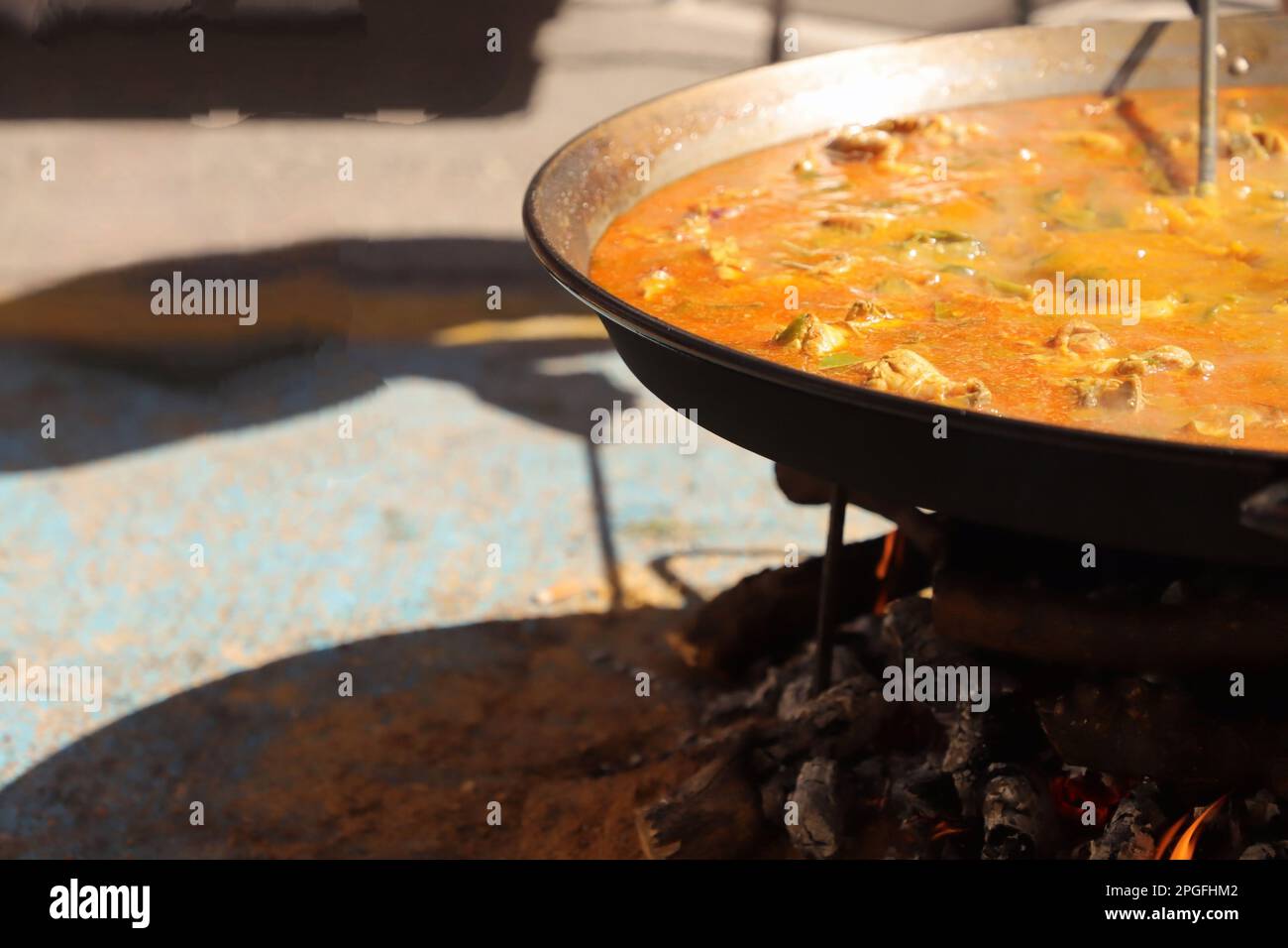 A street traditional cooking with a large stainless steel frying pan in ...