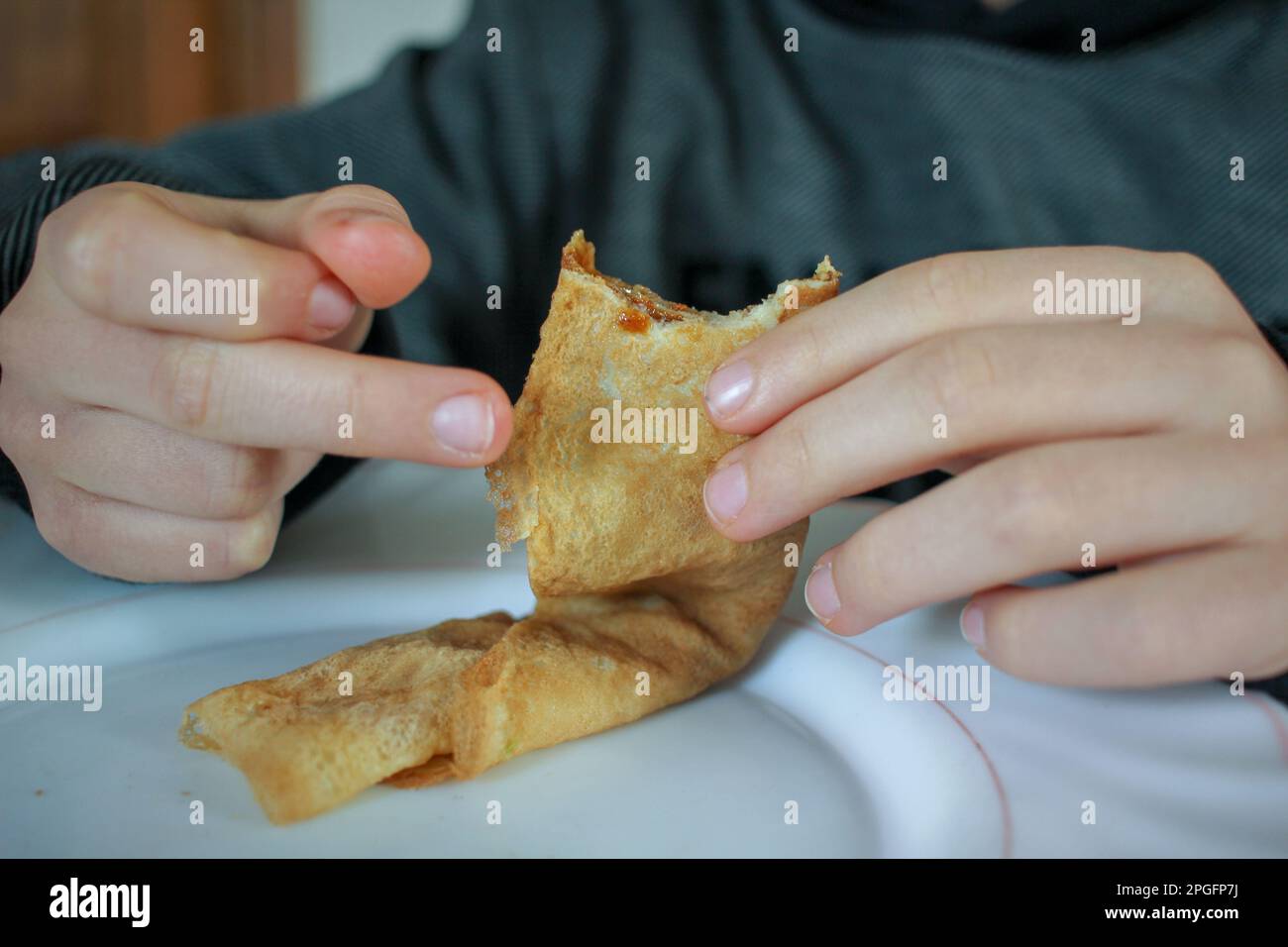 a delicious crepe as a snack in the hands of a young boy Stock Photo ...