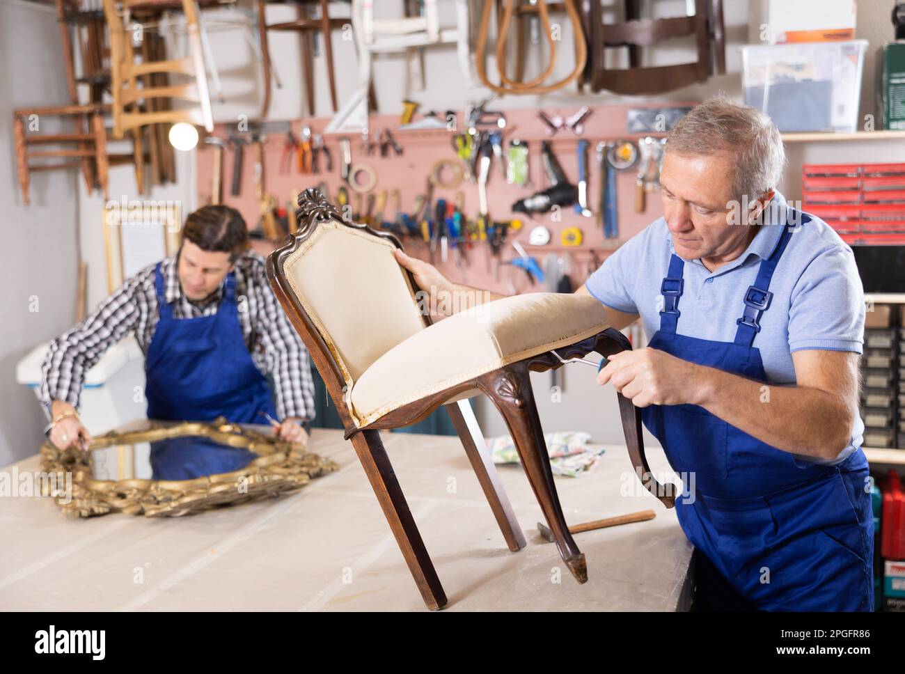 Furniture restorer in process of renovation vintage chair in workshop ...