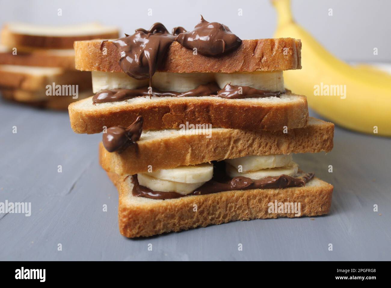 a sweet banana and chocolate paste sandwich on a grey background with ...