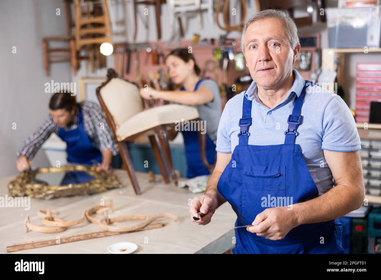 Master restoration worker dressed in overalls poses in working ...