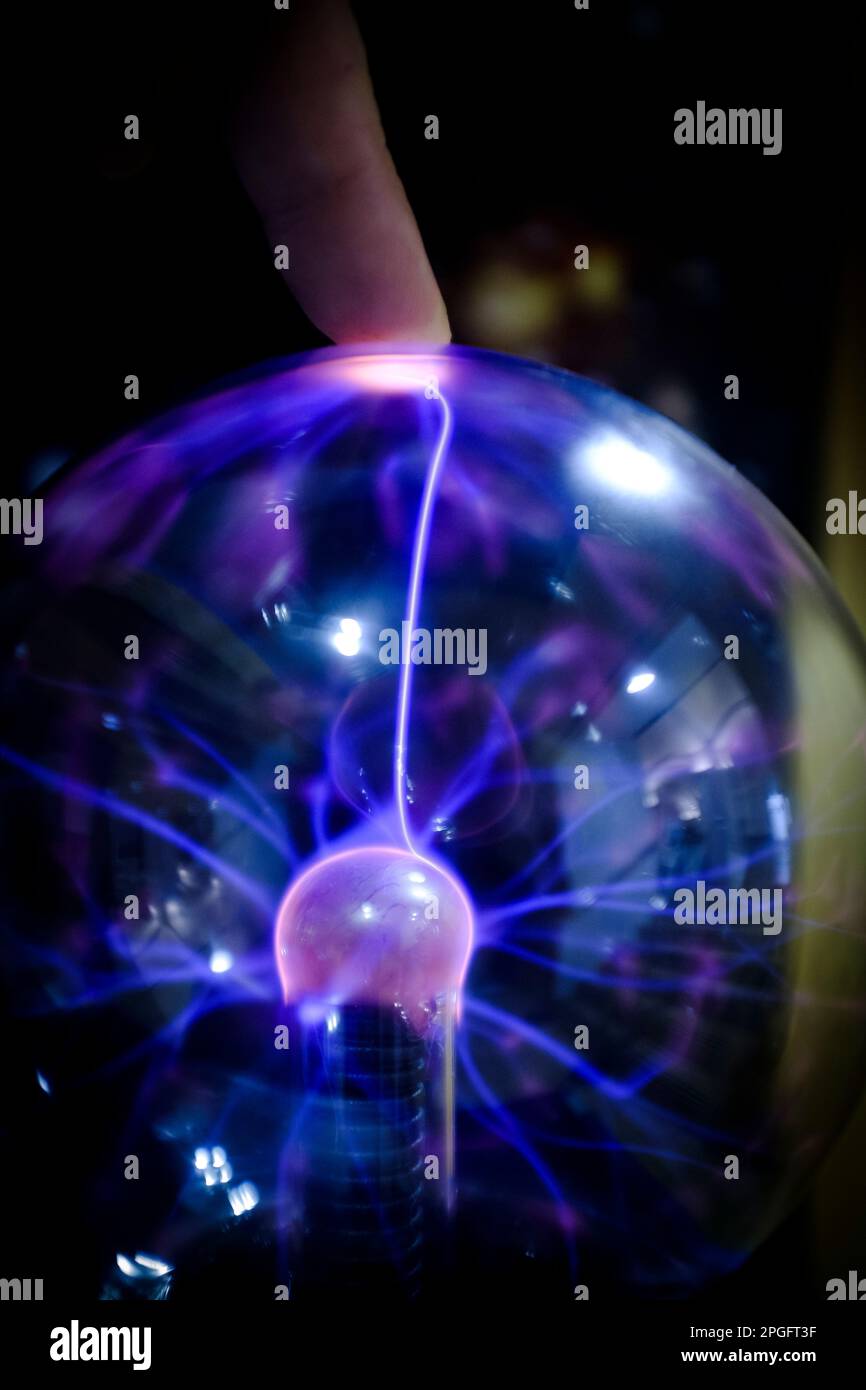Finger touching an energy ball with a lightning light ray crossing a ...
