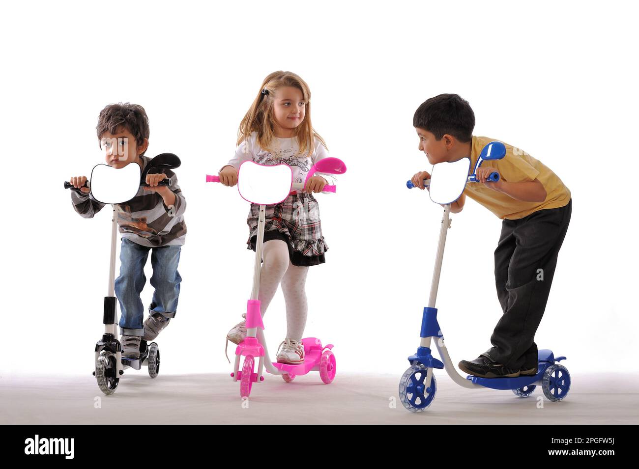 three cute little kids are very happy riding scooter on white ...