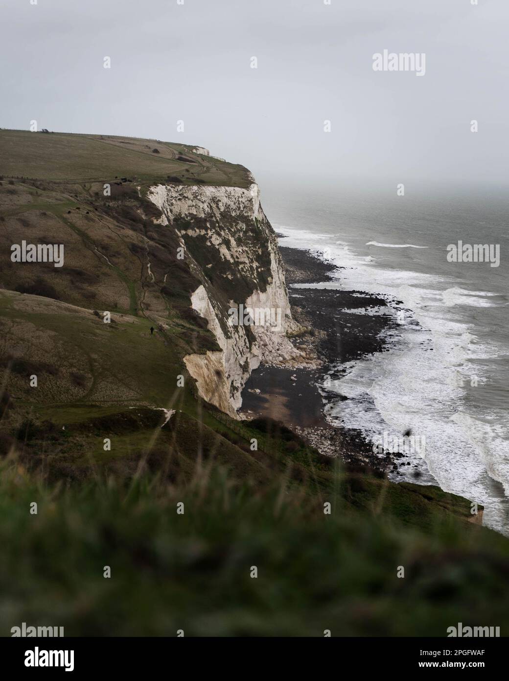 A coastal landscape with a white-chalked beach surrounded by steep ...