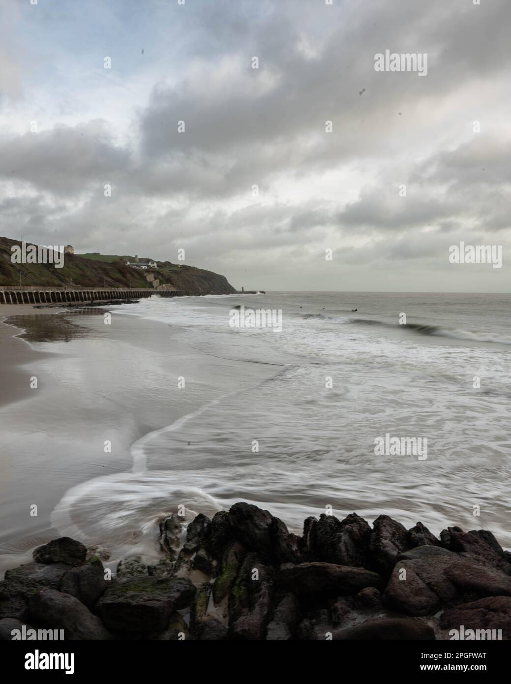 A scenic seascape of a rocky beach with a cliff in the background ...