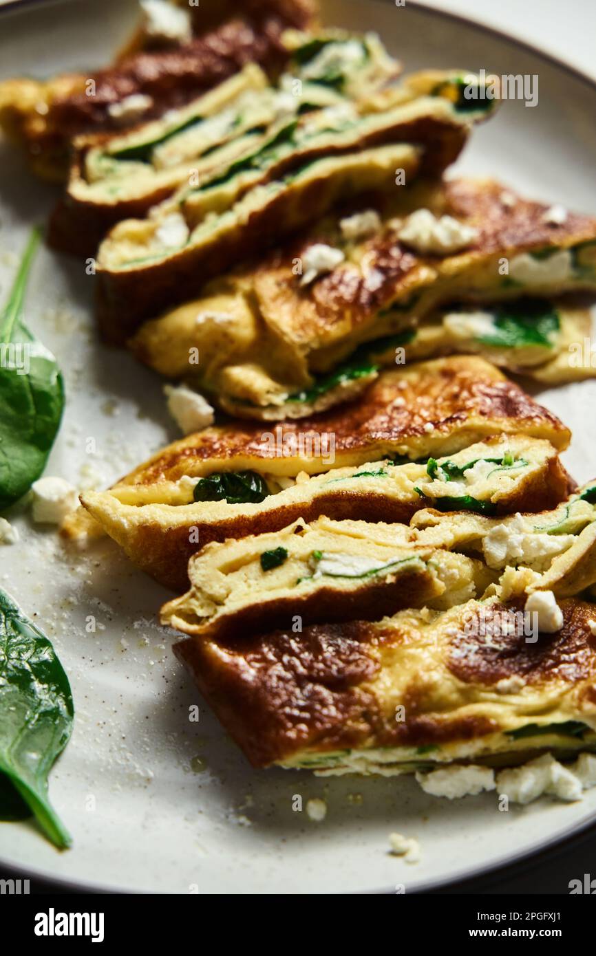Close up of sliced folded omelette stuffed with spinach and feta on the ...