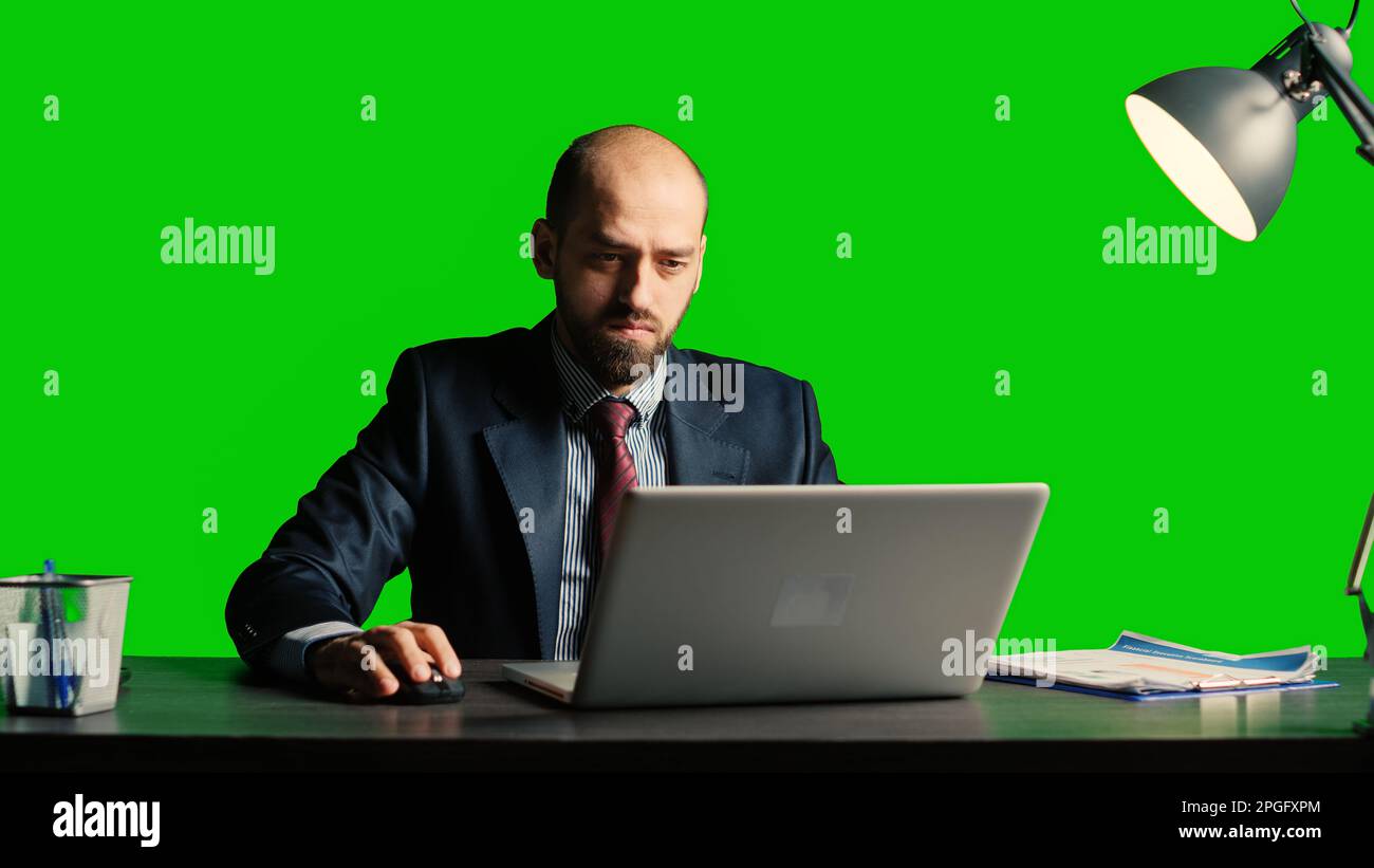 Businessman working on laptop over greenscreen backdrop, using ...