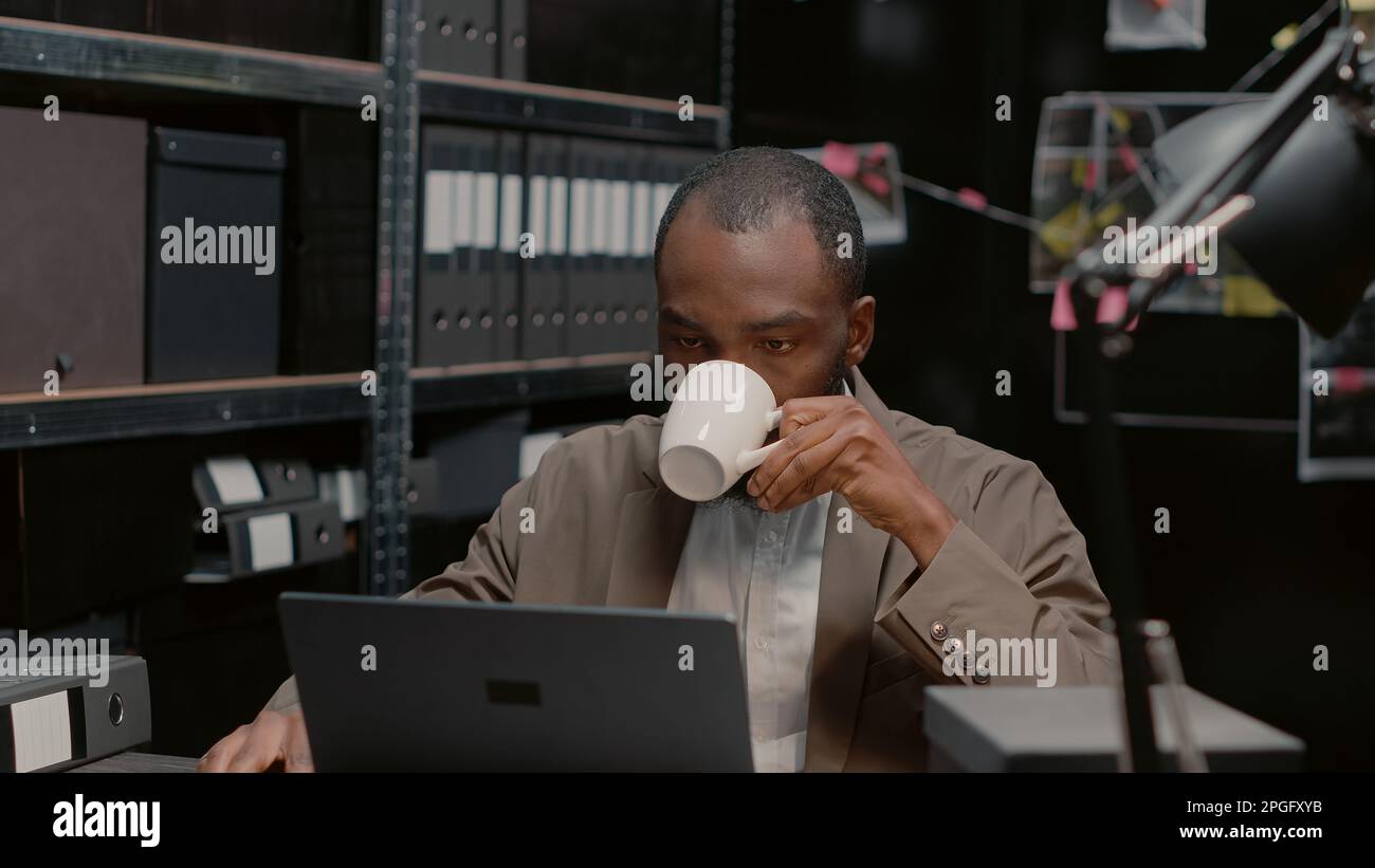 African american law agent studying crime scene photos, looking at ...