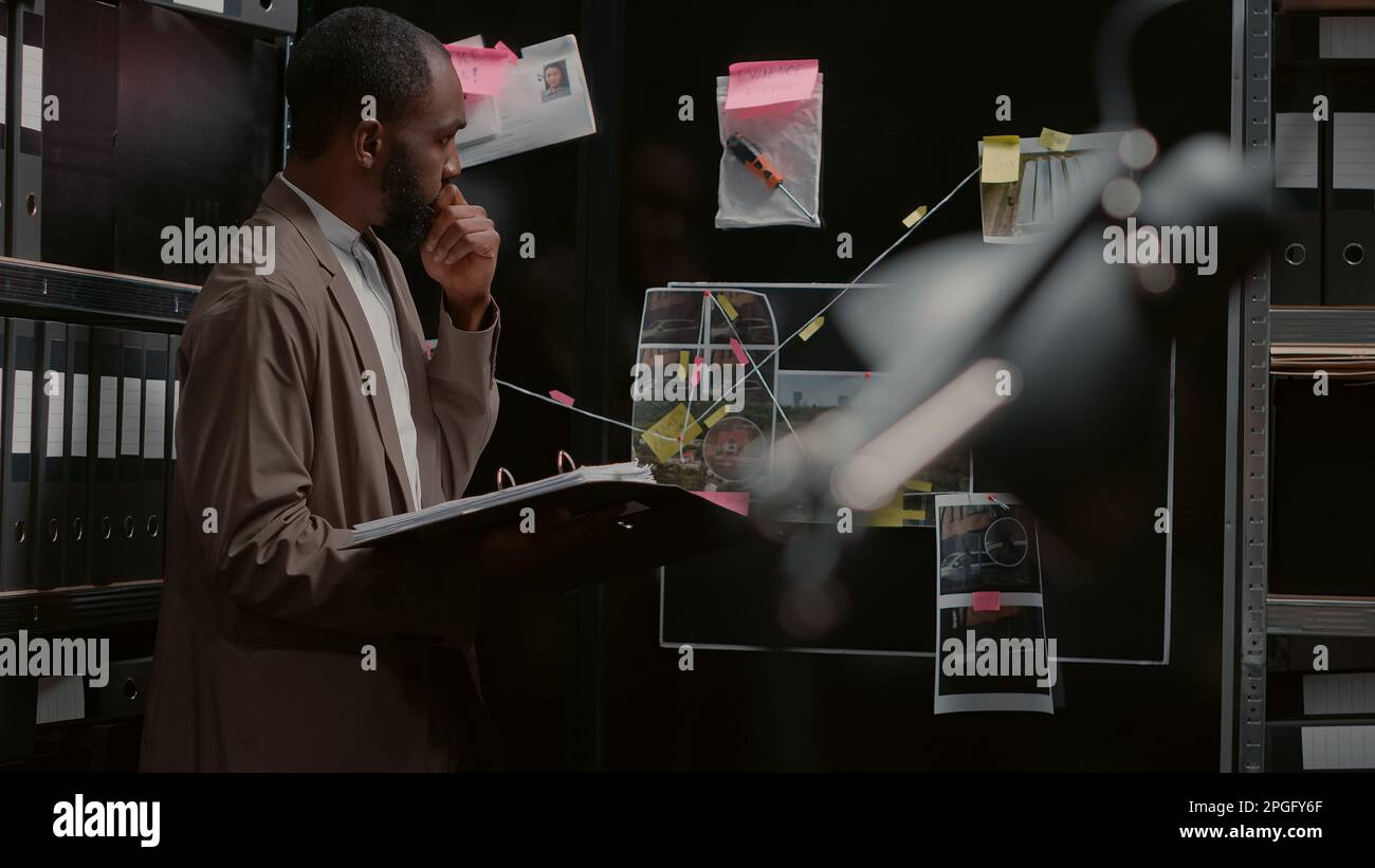 Law enforcement agent looking at detective board, comparing criminal ...