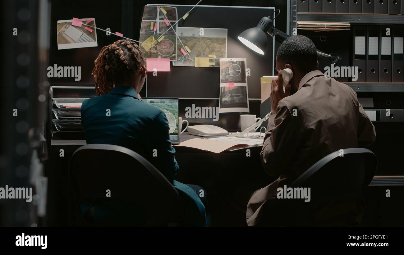 Private investigators examining surveillance photos and reading case ...