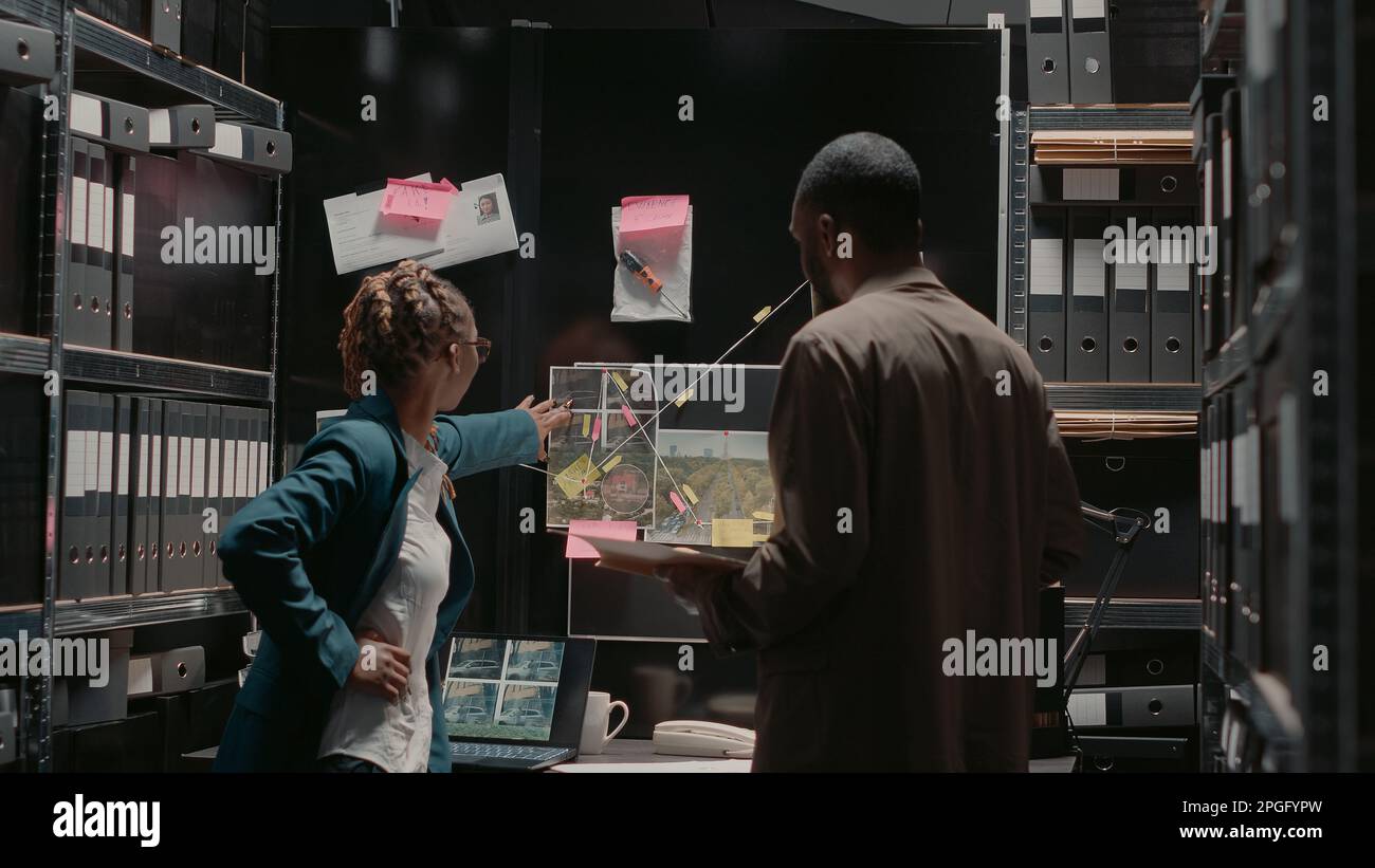 Inspectors studying crime case files in evidence room to find suspect ...