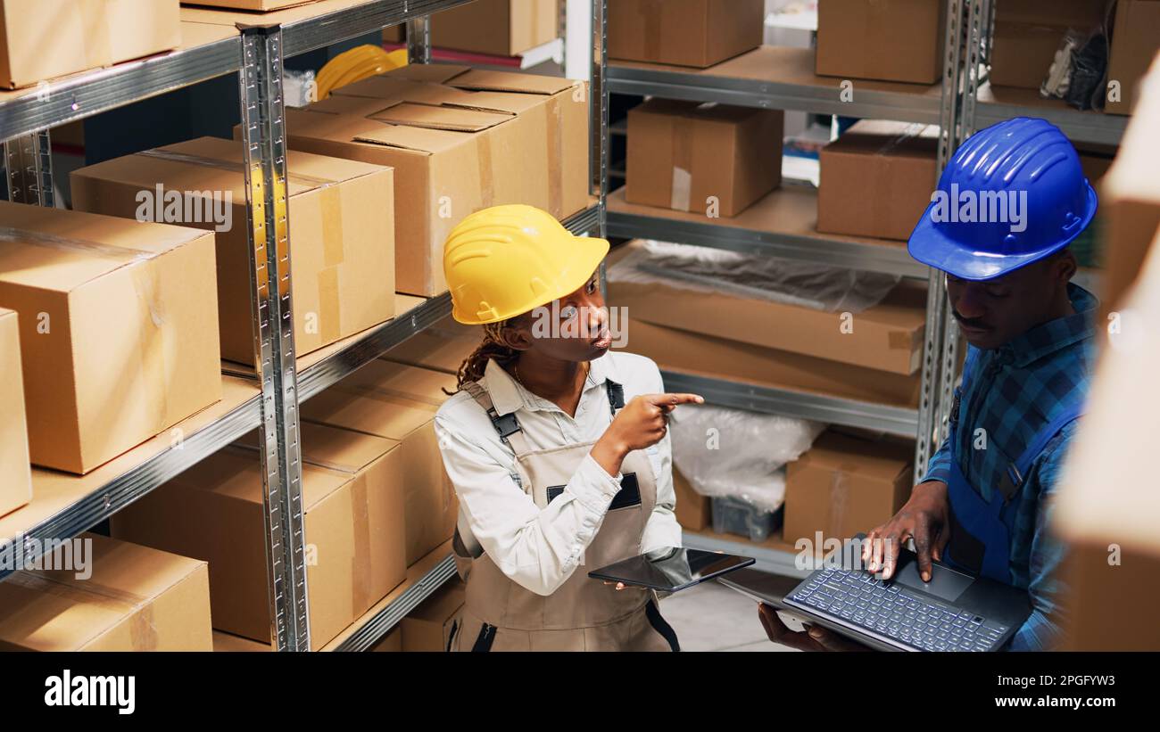 Team of employees checking stock on laptop and tablet, using devices to ...