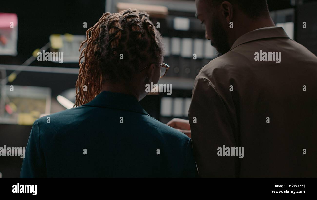 Cops examining evidence photos on detective board map and searching ...