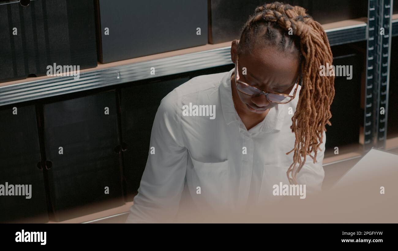 African american woman taking notes on records, trying to find suspect ...