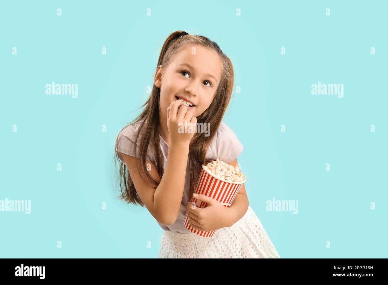 Little girl with popcorn biting nails on blue background Stock Photo ...