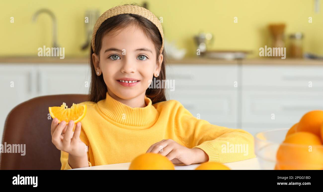 Cute little girl eating oranges in kitchen Stock Photo - Alamy