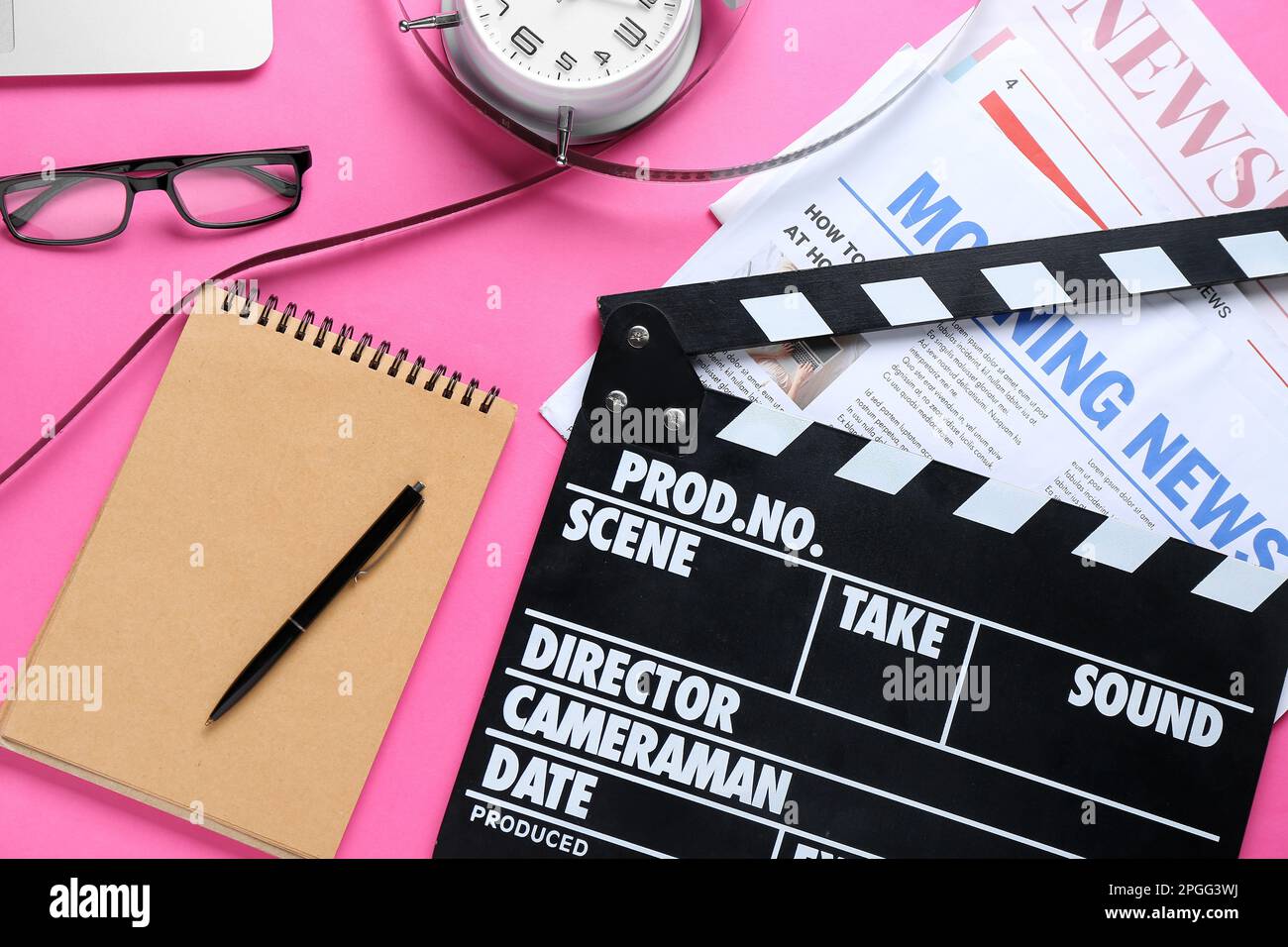 Notebook with movie clapper, film and newspapers on pink background ...