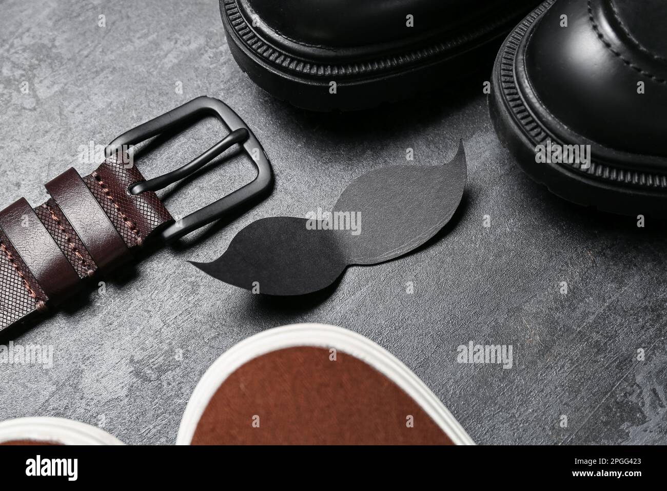 Paper mustache with male shoes and belt on dark background, closeup ...