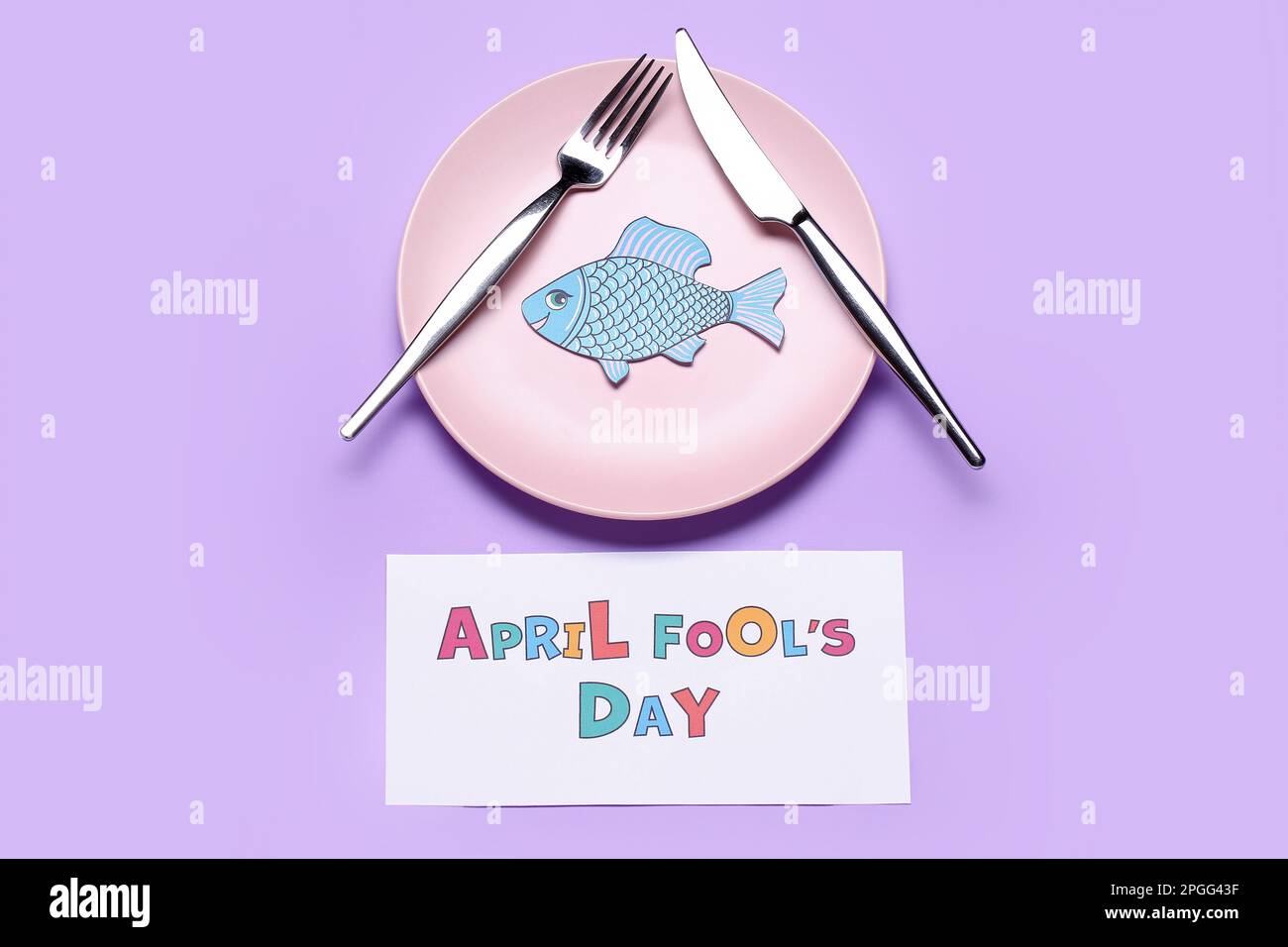 Paper with text APRIL FOOL'S DAY, fish and table setting on lilac ...