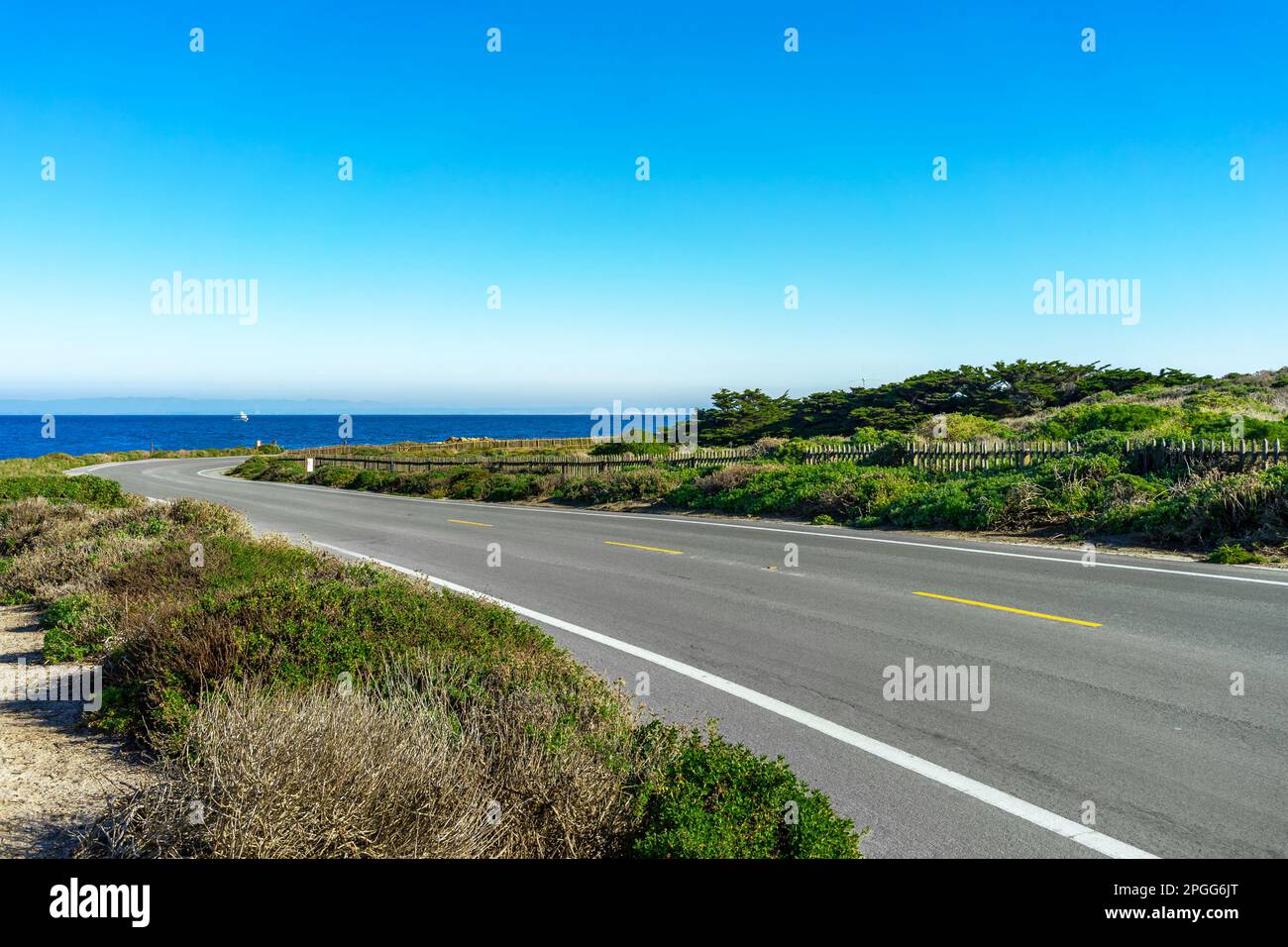 A empty rural road withe green landscape next to the Pacific Ocean ...