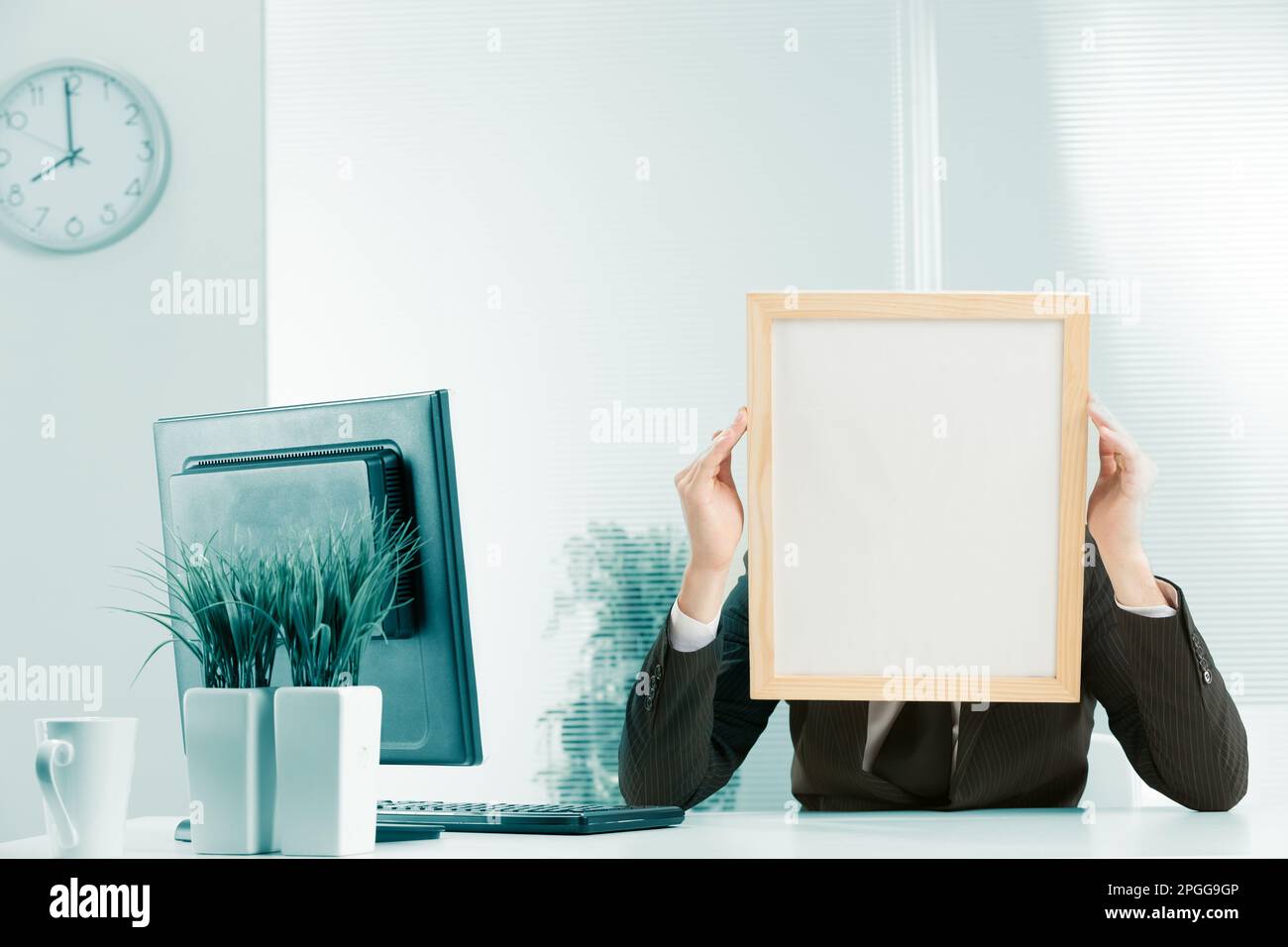 Office workplace, a sign-headed man framed in light wood holds the sign ...