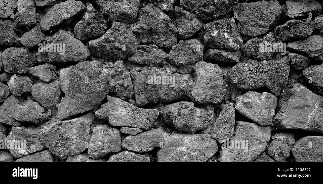 Frontal view of a black quarry stone wall made of large black rough ...