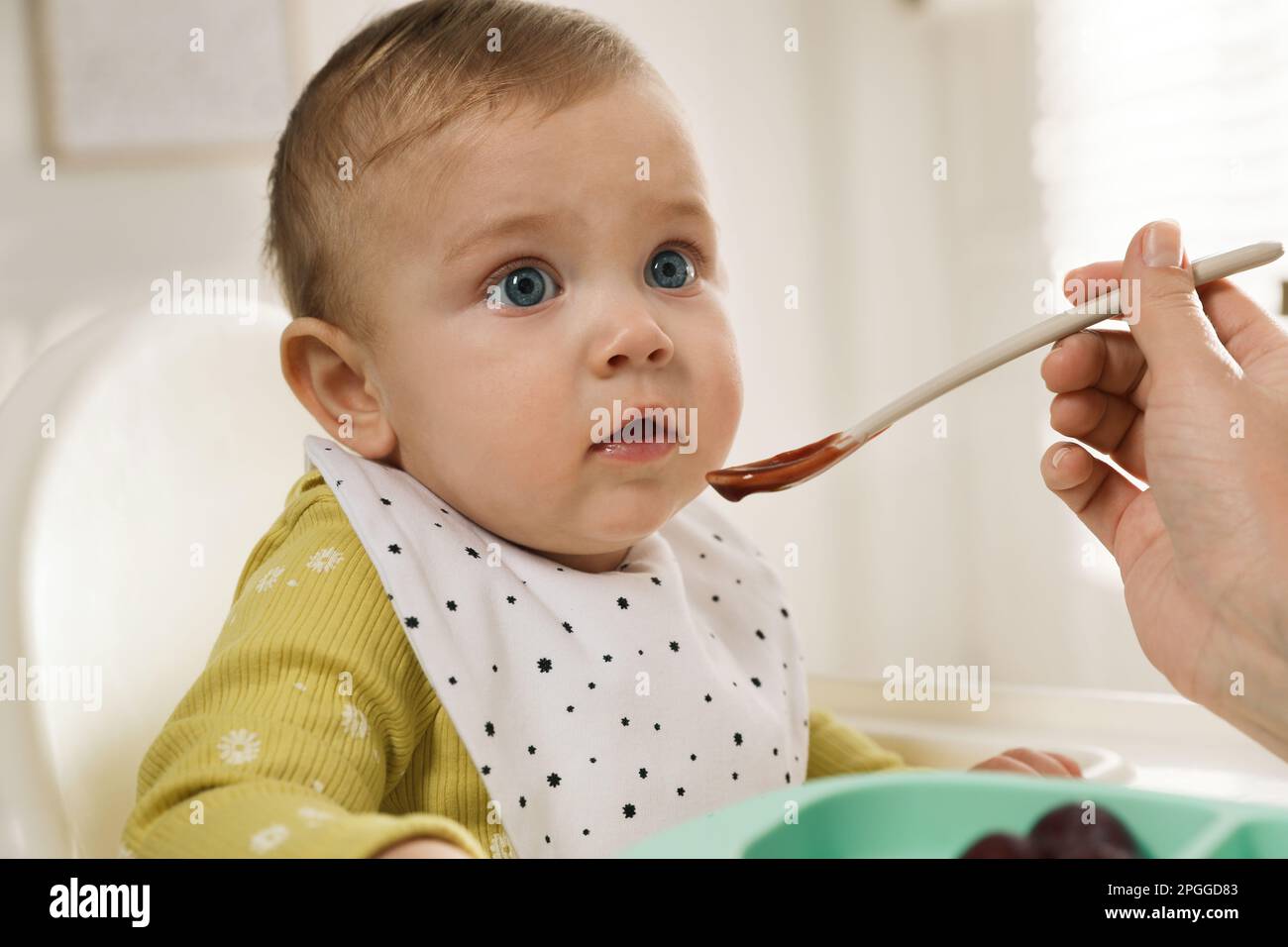 Mother feeding her little baby at home. Kid wearing bib Stock Photo - Alamy